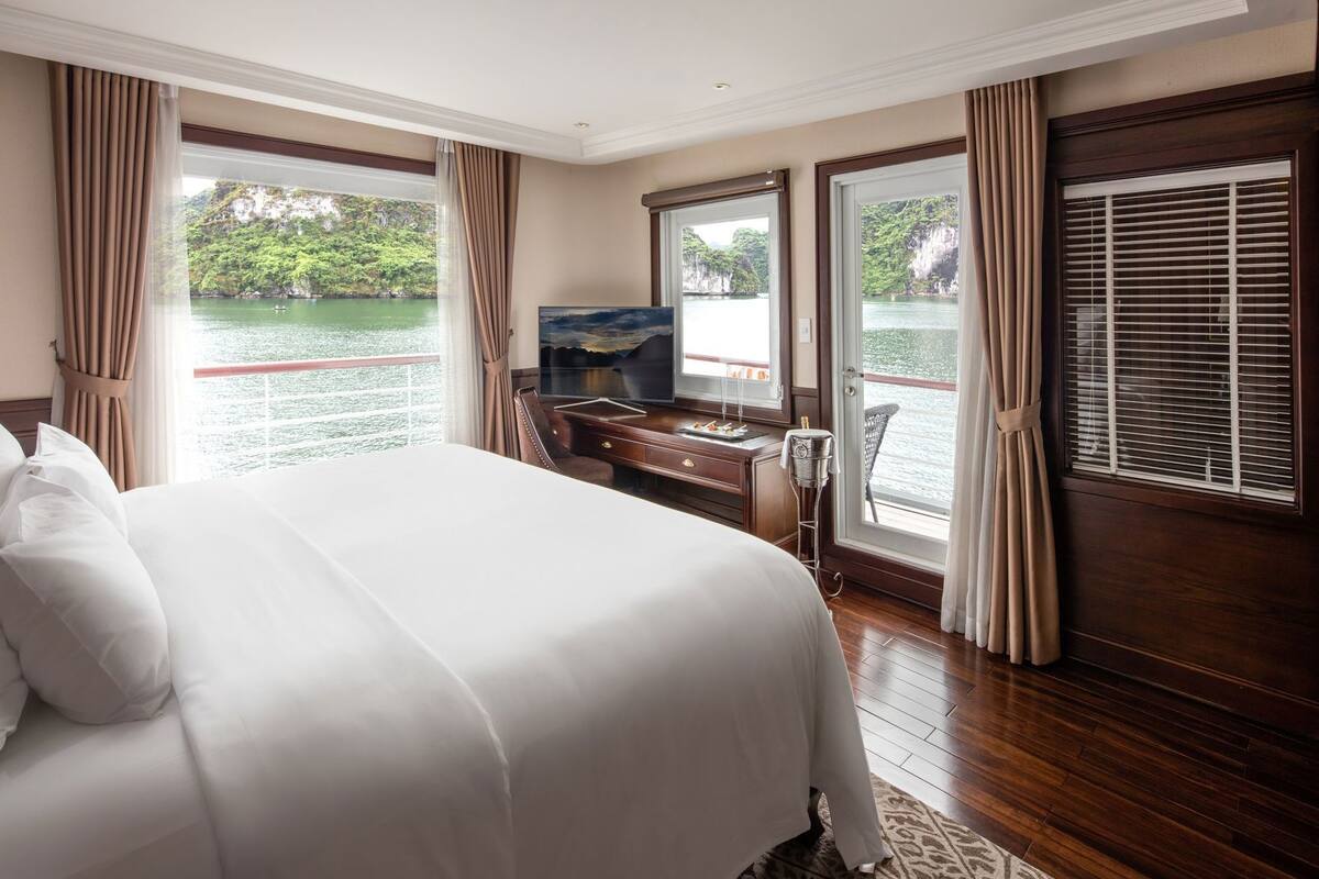 Quarto de hotel com uma cama grande, uma escrivaninha e vista para a água.