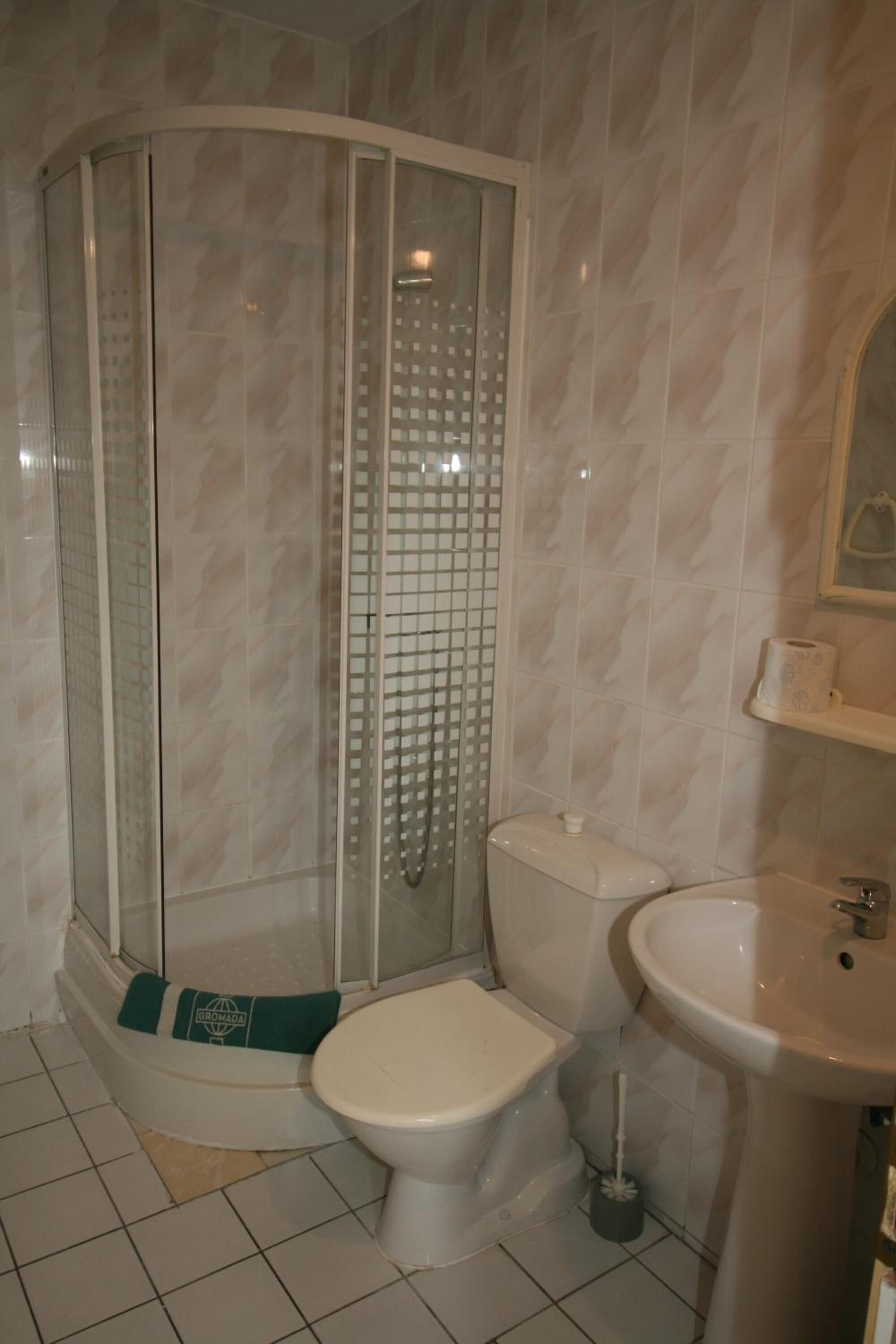 Casa de banho com cabine de duche, sanita e lavatório.