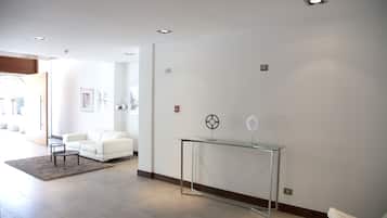 Uma sala de estar moderna com um sofá branco, uma mesa de centro de vidro e um console minimalista com objetos decorativos.
