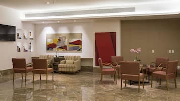 Um hall moderno com área de estar, uma grande pintura abstrata e uma TV de tela plana na parede.