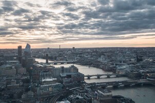 Vista panorâmica de um horizonte urbano com rio, pontes e edifícios históricos.