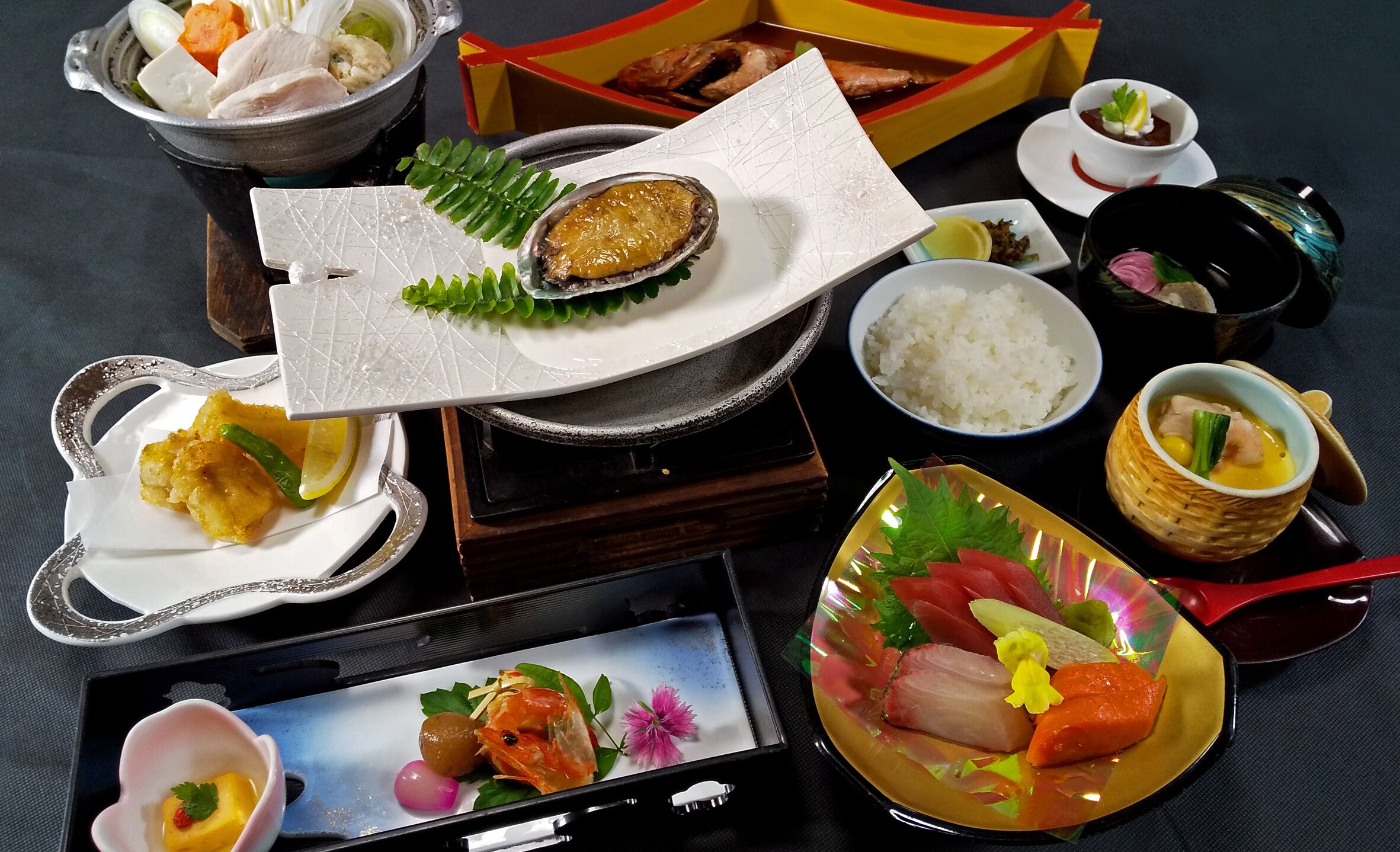 Diversos pratos japoneses, incluindo sushi, sashimi e tigelas de arroz, dispostos sobre uma mesa.