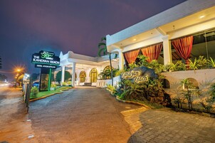Exterior do hotel The Kandyan Reach, com entrada bem iluminada, uma placa de sinalização e um caminho que leva ao edifício principal.