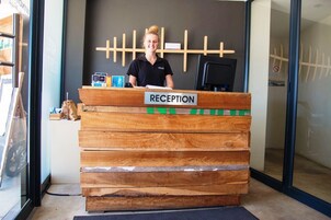 Uma mesa de recepção com uma placa identificada como 'RECEPTION' em um edifício moderno, com balcão de madeira e placa na parede.