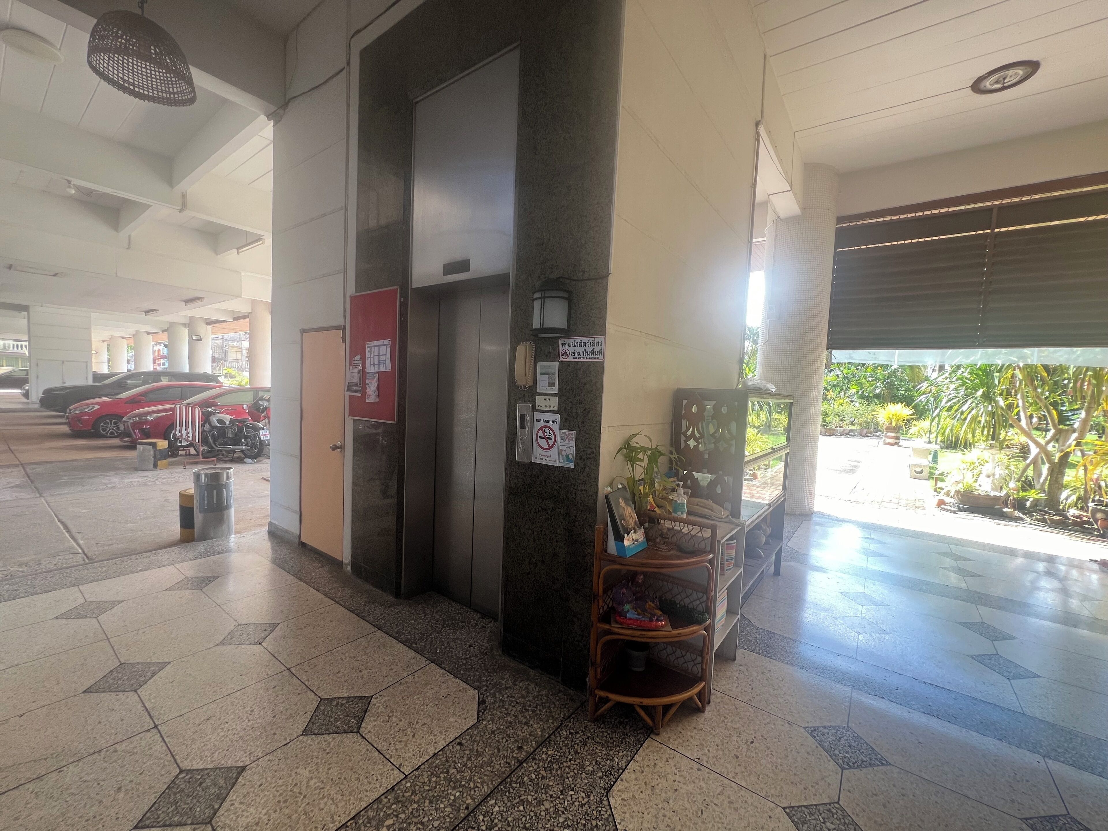 Uma garagem com carros, um elevador e uma receção com uma planta.