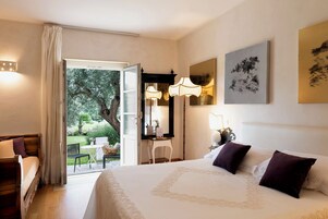 Quarto com uma cama grande, uma escrivaninha e uma cadeira, janela com cortinas e obras de arte nas paredes.