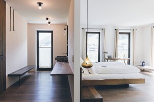 Quarto moderno com uma cama grande, mesa de cabeceira e vista para o exterior.