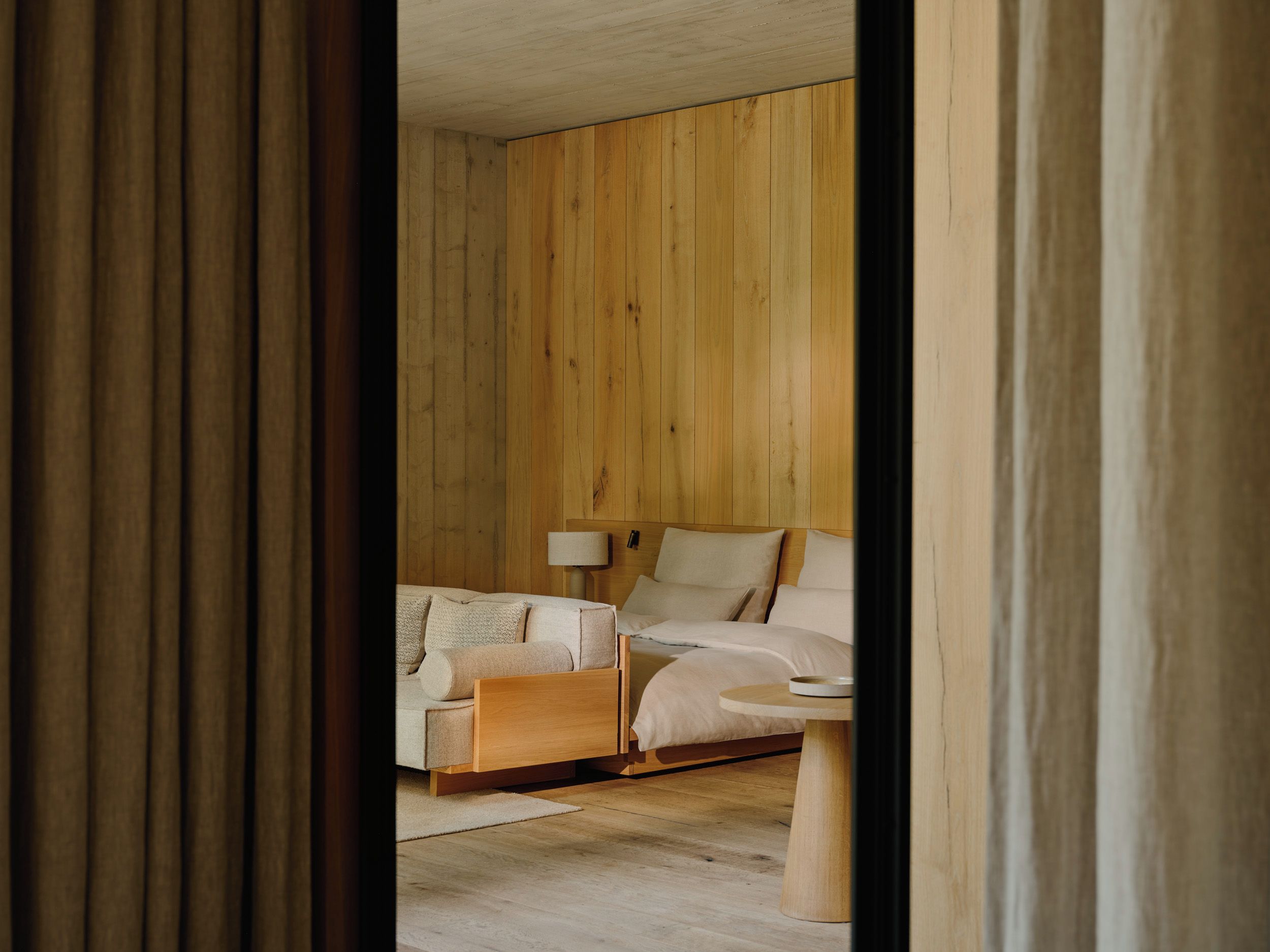 Quarto com cama, mesa de cabeceira e luminária.