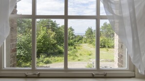 Janela com vista para uma paisagem verde e uma parede de tijolos.
