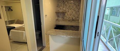 Quarto compacto com cozinha compacta, uma cama pequena e banheiro.