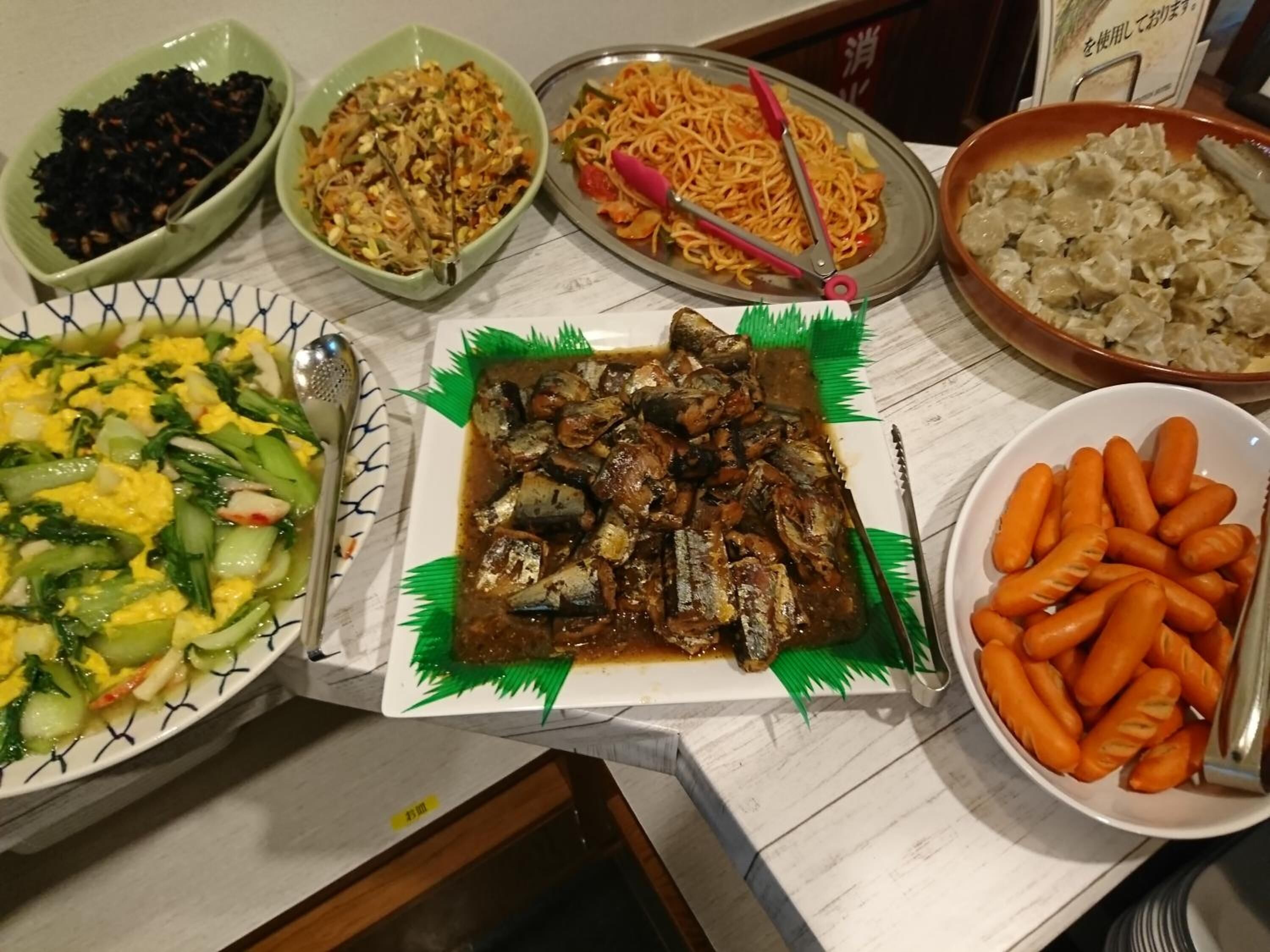 Diversos pratos, incluindo um prato de carne, legumes e macarrão, além de tigelas de cenoura e outros acompanhamentos.