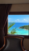 Quarto com vista para uma praia tropical e oceano.