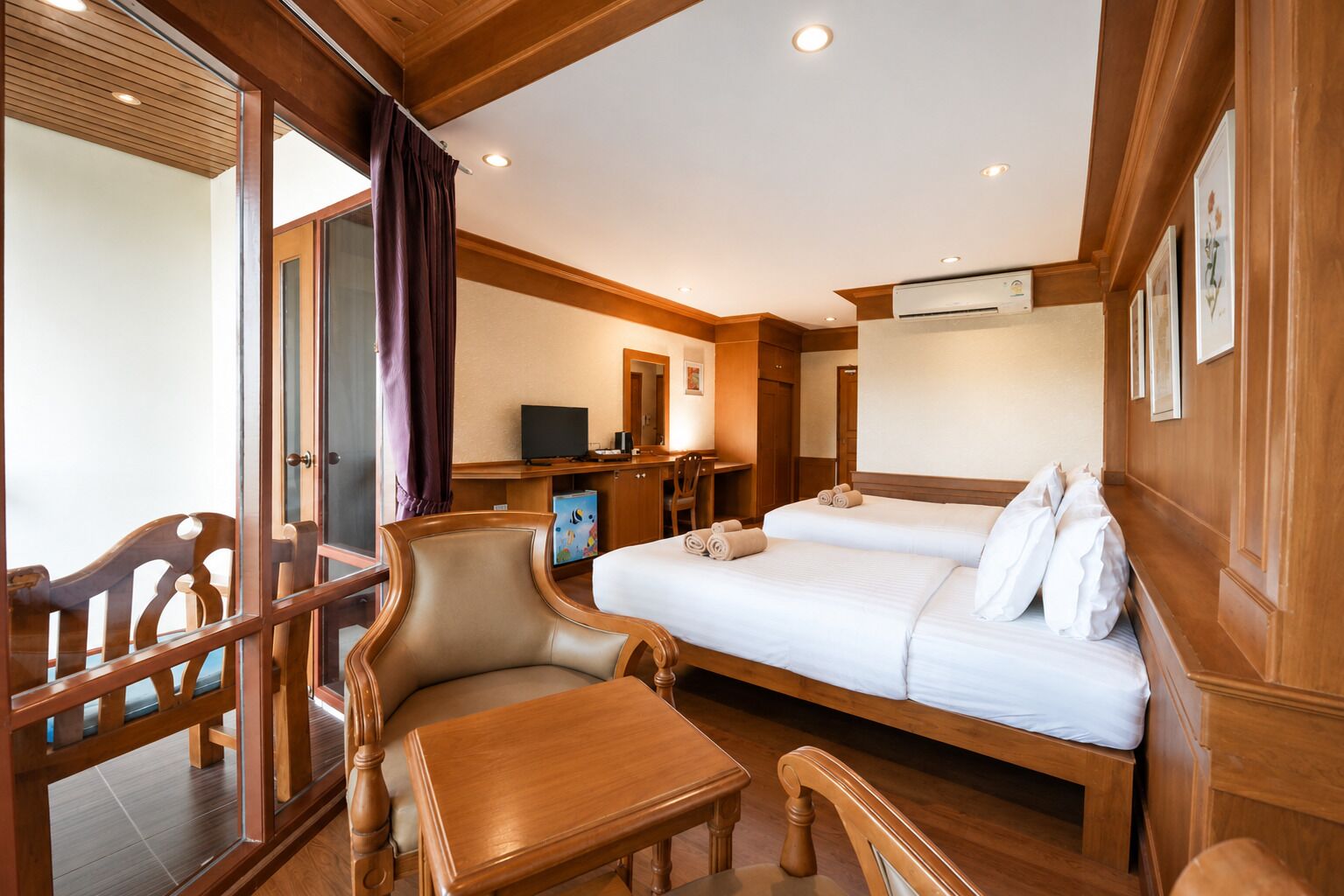 Quarto de hotel com uma cama grande, uma escrivaninha, uma cadeira e uma televisão.