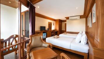 Quarto de hotel com uma cama grande, uma escrivaninha, uma cadeira e uma televisão.