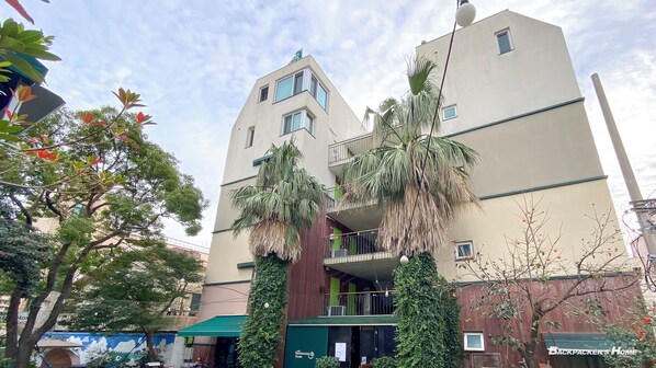 Um edifício com vários andares, teto plano, janelas grandes e varanda no segundo pavimento.