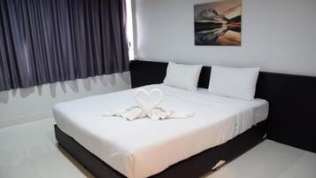 Cama bem arrumada com lençóis brancos e arranjo de toalhas em formato de coração.
