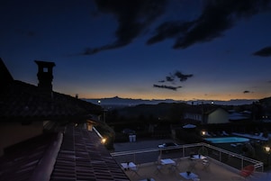 Terraço no topo do edifício com piscina, área de estar ao ar livre e vista para a paisagem circundante.