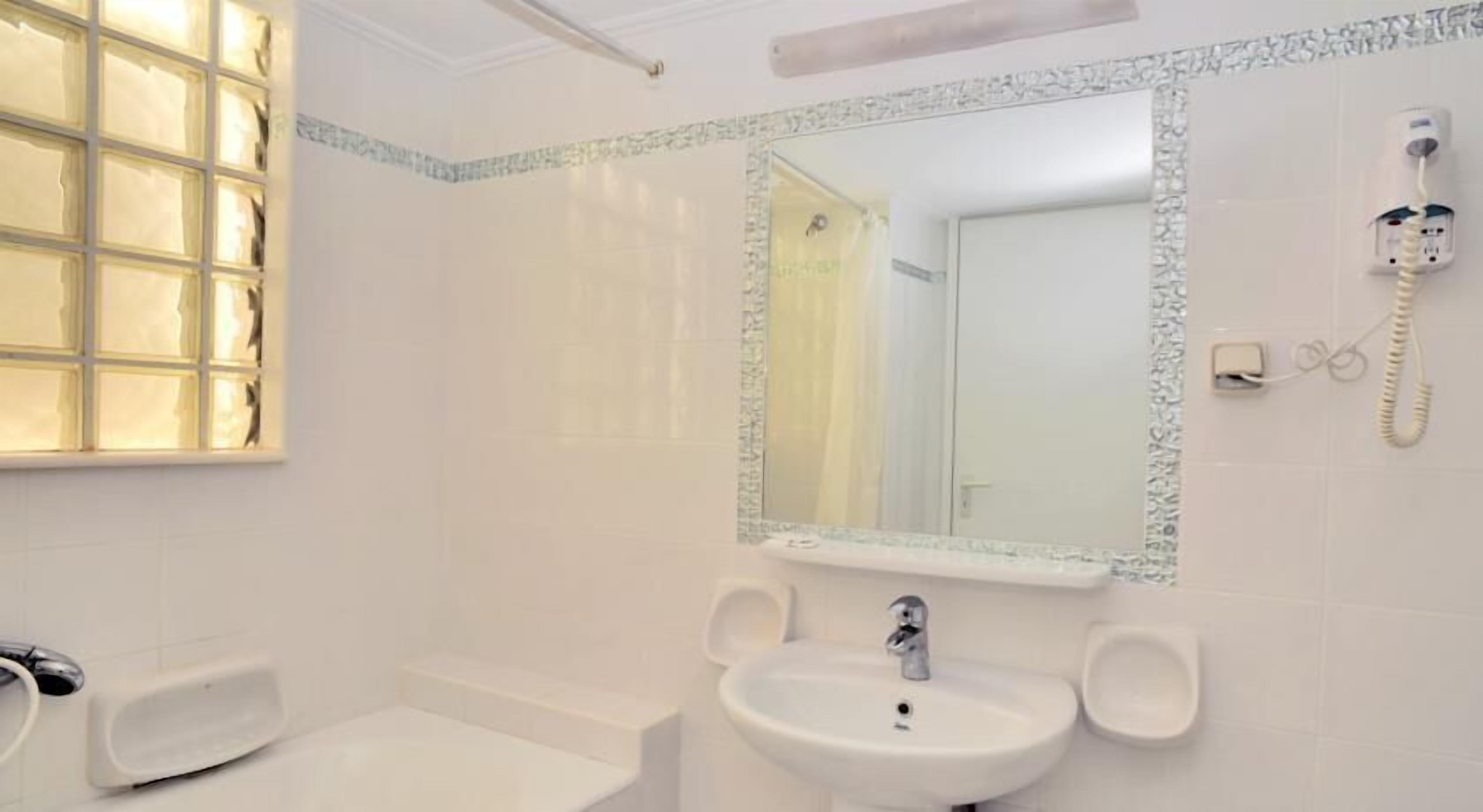 Casa de banho com lavatório branco, espelho e telefone.