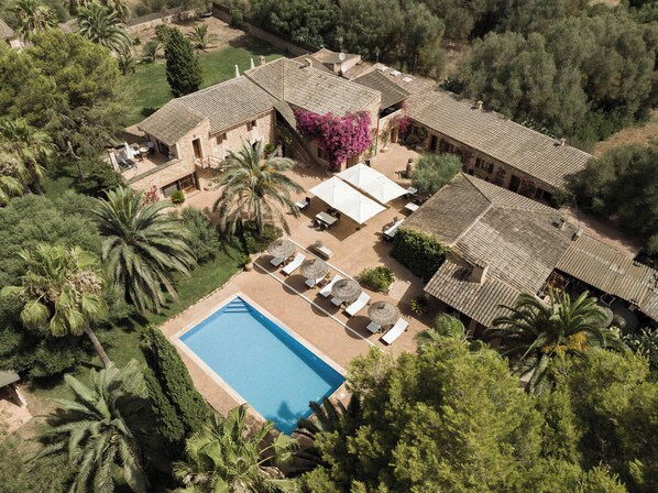 Vista aérea de uma villa com piscina, área de estar externa e vegetação exuberante.