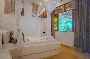 Um quarto com cama de dossel, janela com vista para o verde e cortina no lado direito.