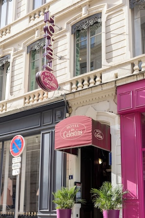 Placa de hotel com 'HOTEL des Celestins' e um aviso de 'proibido estacionar'.