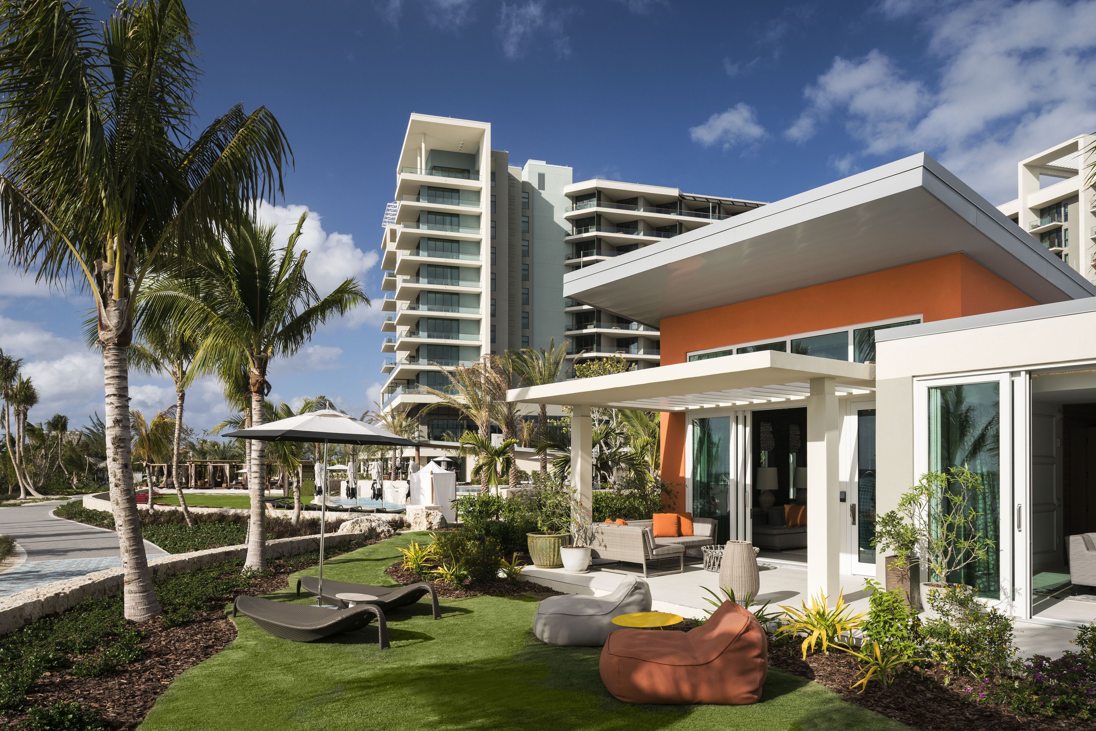 Um hotel moderno com área de piscina, espaço ao ar livre e palmeiras.