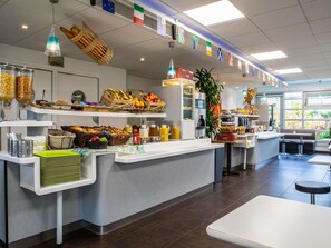 Uma mesa de pequeno-almoço com diversas opções de comida e uma área de estar com vista para o exterior.