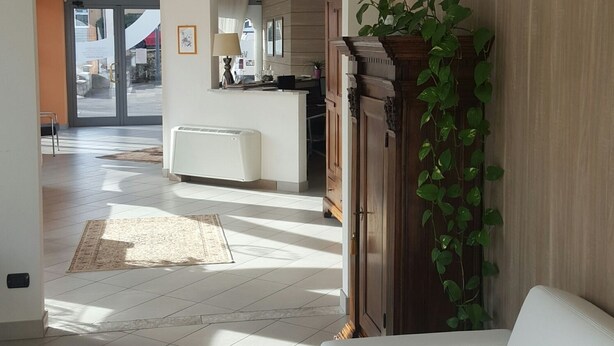 Uma sala de estar espaçosa com um sofá branco, um armário de madeira e um vaso de planta.