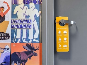Uma porta com uma placa amarela que detalha os serviços do hotel, incluindo Wi-Fi, estacionamento e recepção 24 horas.