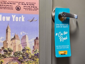 Uma porta com uma etiqueta azul da hotelF1 exibindo o horizonte de Nova York e uma mensagem em francês.