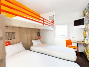 Quarto de hotel compacto com duas camas de solteiro, uma escrivaninha com cadeira, televisão e janela.