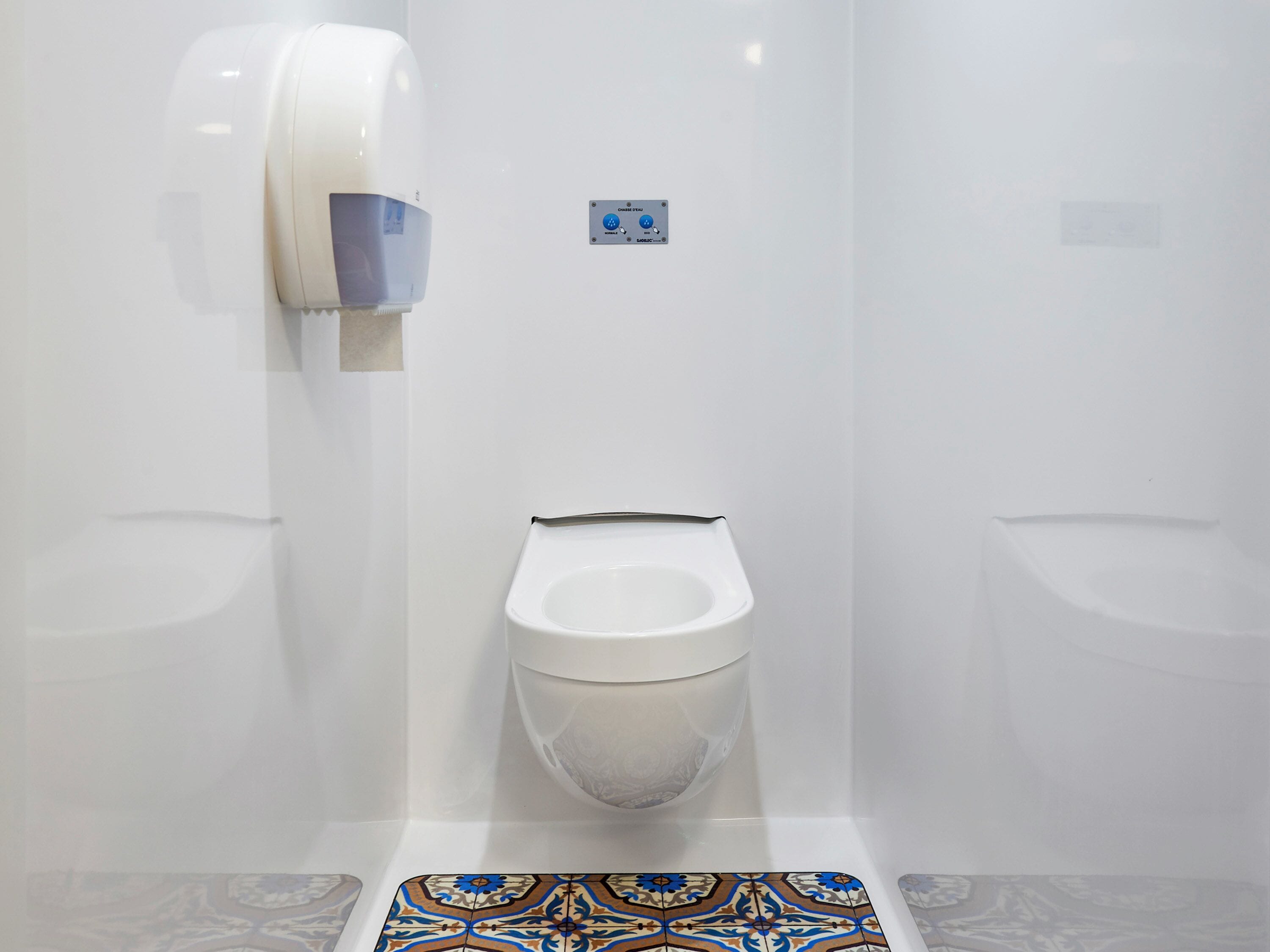 Uma casa de banho moderna com sanita, urinol e secador de mãos.