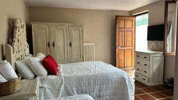 Quarto com duas camas, cômoda, guarda-roupa e televisão.