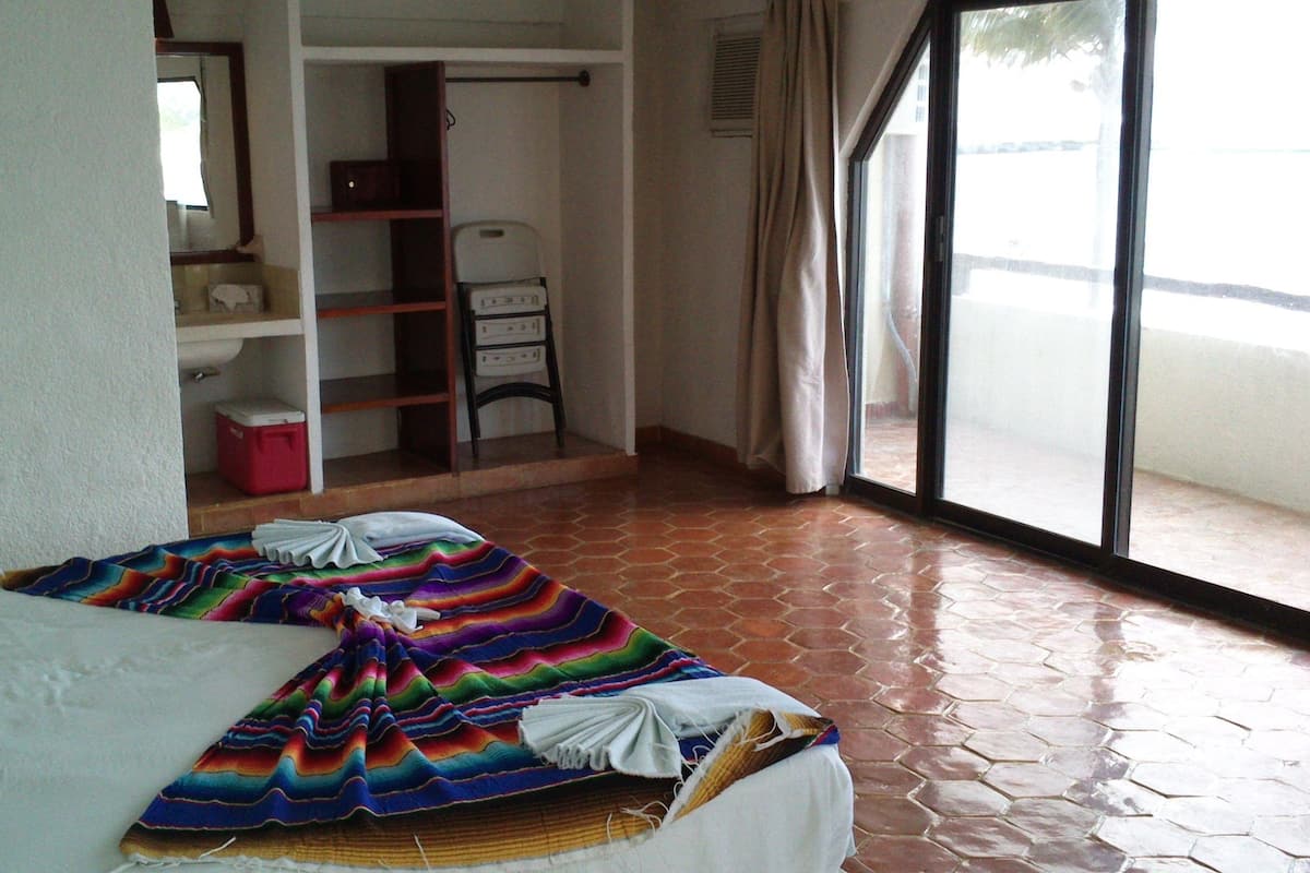 Quarto com cama, janela, guarda-roupa e chão em mosaico.