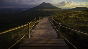 Uma trilha de madeira que leva ao cume de uma montanha, com uma barreira de corda de cada lado.