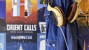 Cartaz com os dizeres 'Orient Calls' e 'Washington', um par de fones de ouvido e uma jaqueta jeans.