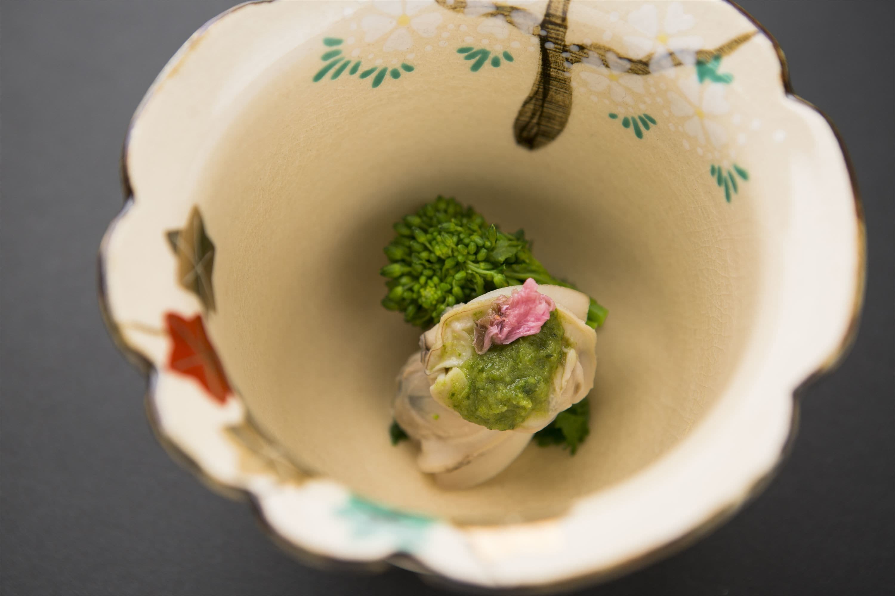 Uma tigela com padrão floral e guarnição verde.