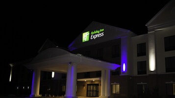 Edifício Holiday Inn Express à noite, com letreiros iluminados e entrada coberta.