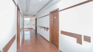 Corredor com painéis de madeira, piso polido e porta com uma placa.