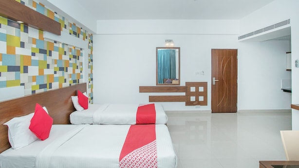 Quarto de hotel com duas camas, um ventilador de teto, um espelho e uma porta de madeira.
