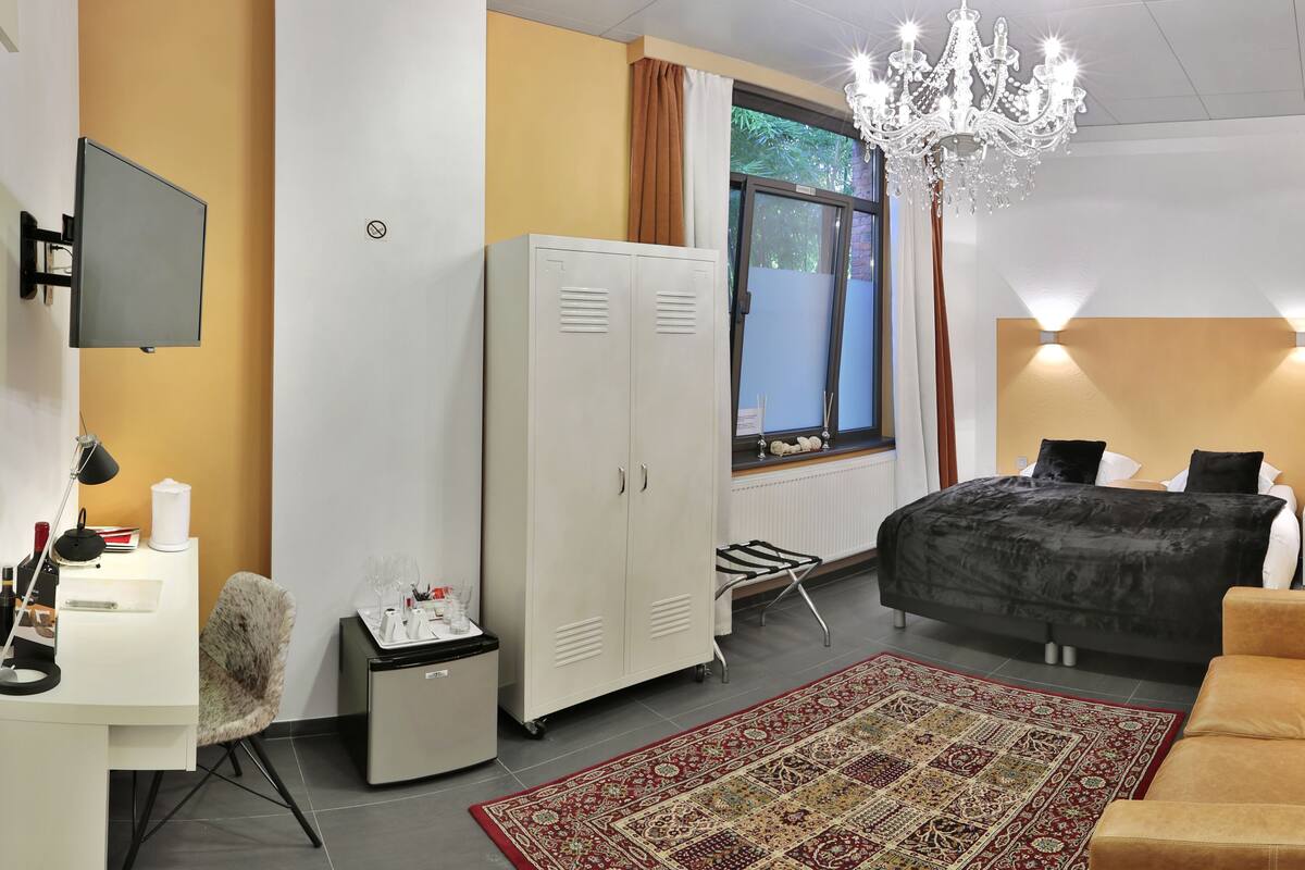 Quarto com cama, escrivaninha, guarda-roupa, cadeira, mesa pequena, candelabro e tapete grande.
