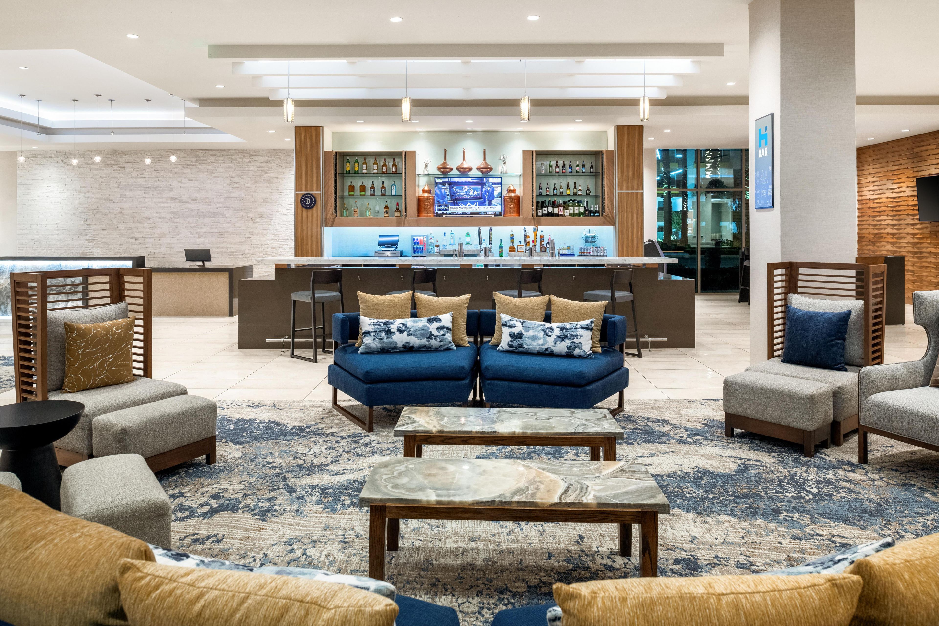 Um lobby moderno com área de bar, espaços de estar e uma grande janela.