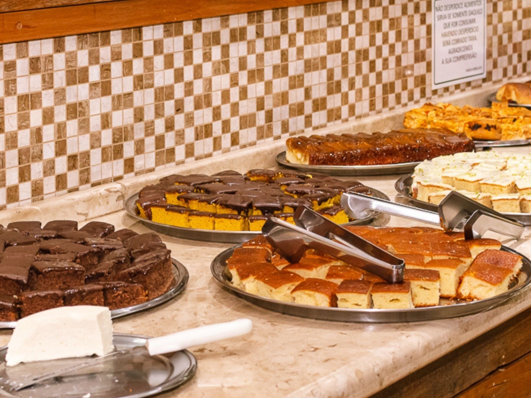 Buffet com diversos doces, como bolos e brownies.