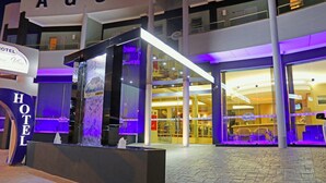 Entrada de hotel com uma placa grande com a palavra 'ÁGUA' e uma área de recepção de design moderno.