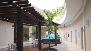 Uma área externa coberta com deck de madeira, assentos e plantas em vasos.