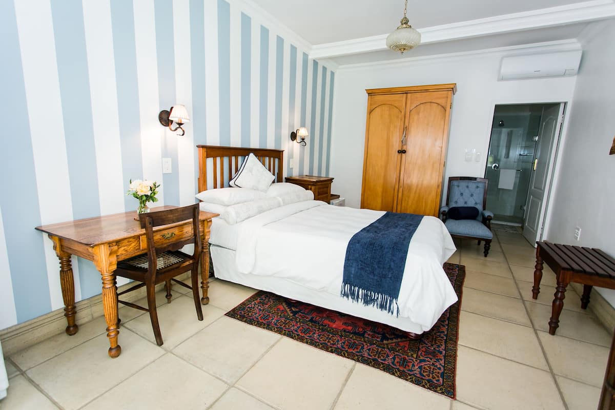 Quarto com cama, escrivaninha de madeira, cadeira e guarda-roupa.