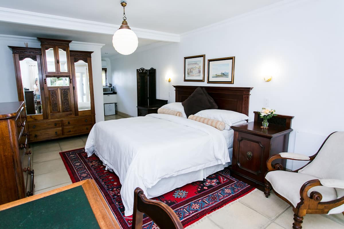 Quarto com uma cama grande, penteadeira de madeira e uma cadeira.
