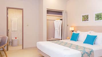 Quarto de hotel com cama, roupão, toalha, cadeira e pequena mesa com abajur.