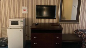 Quarto de hotel com micro-ondas, televisão, cómoda e espelho.