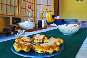 Uma mesa de café da manhã com waffles, um prato de ovos e uma garrafa de suco.